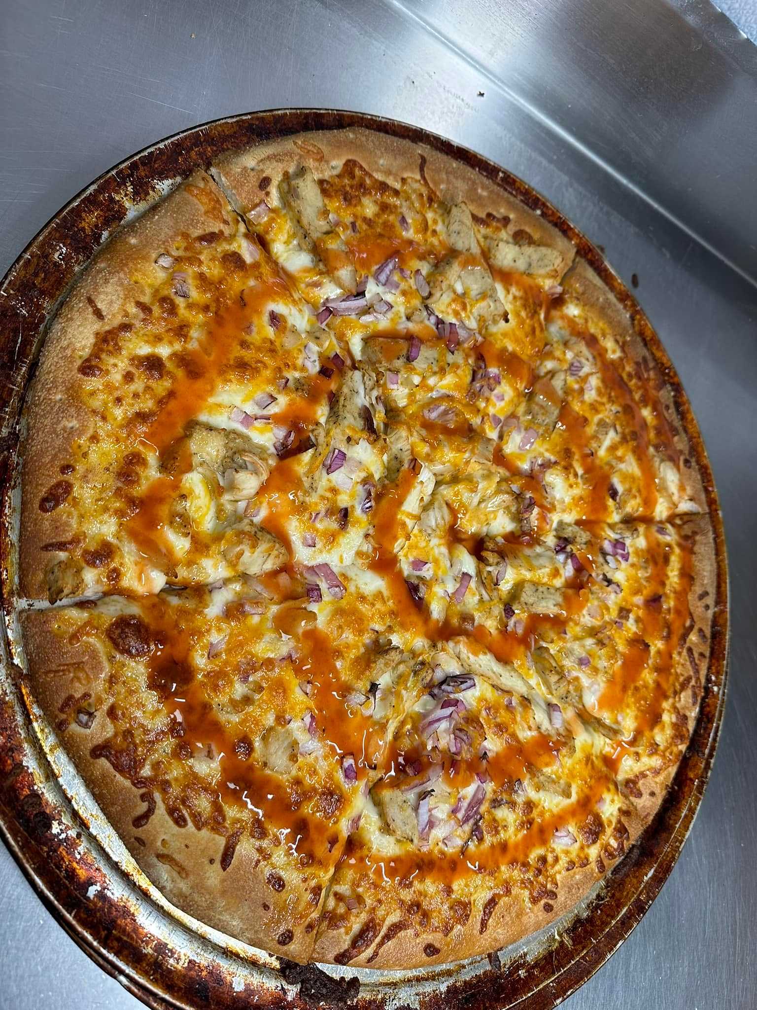 Buffalo chicken pizza with cheese, red onions, and a drizzle of hot ...