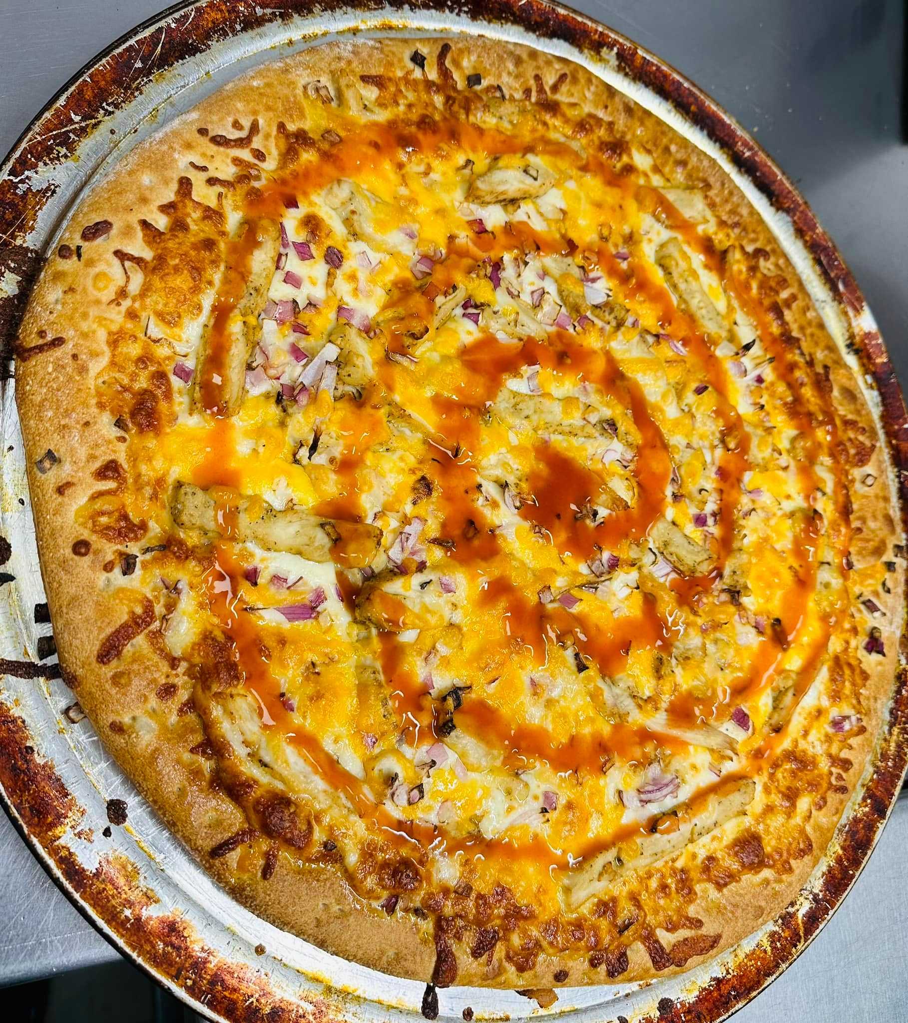 Cheese pizza with buffalo sauce drizzle, red onions, and light char ...
